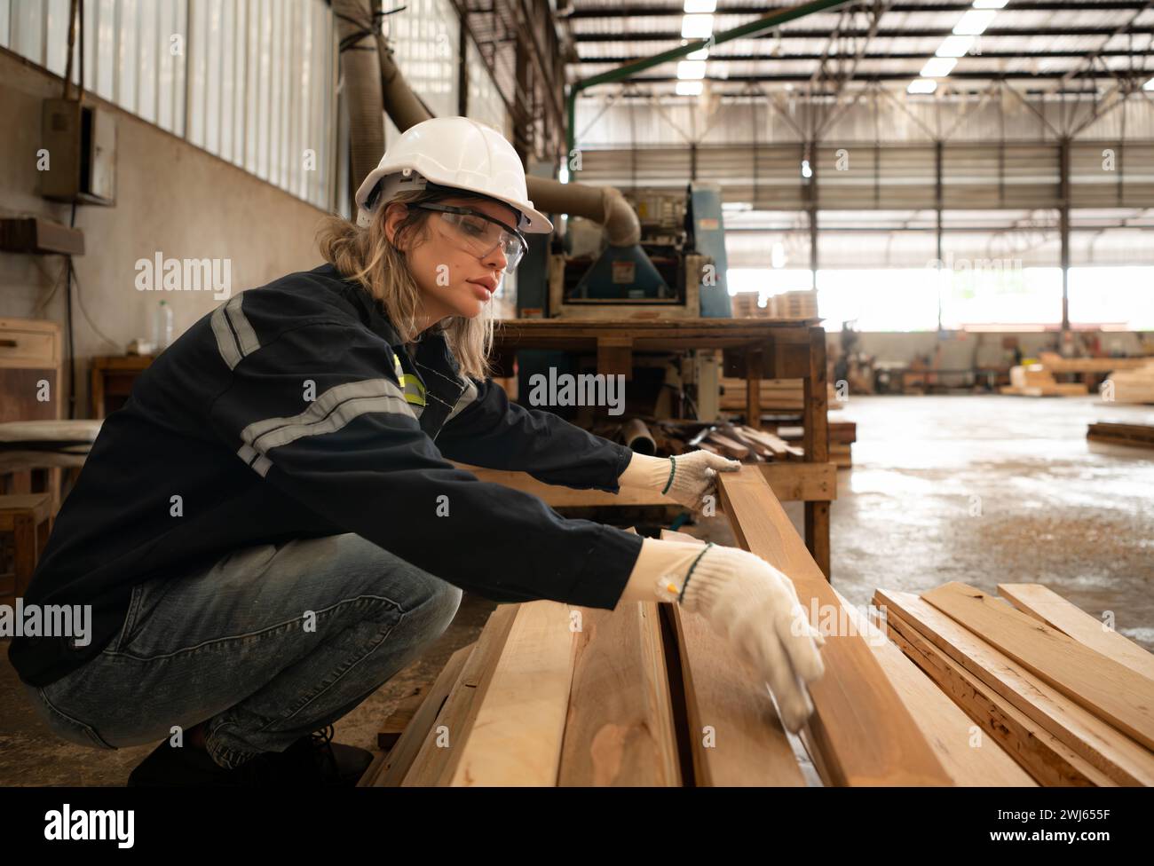 A carpenter works in a carpentry workshop. She collects the wood that ...