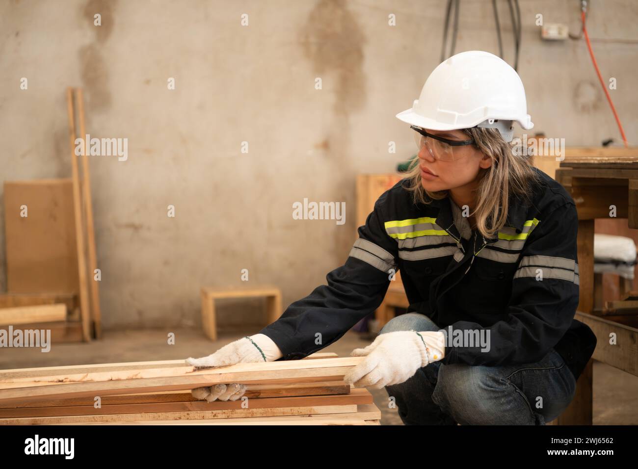 A carpenter works in a carpentry workshop. She collects the wood that ...