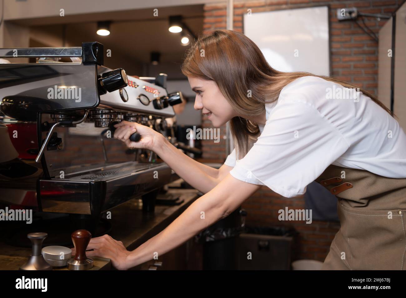 Young female barista preparing coffee in cafe. Female barista using ...