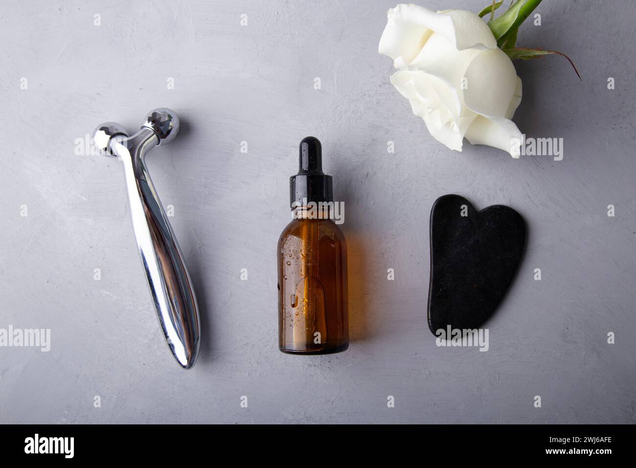 Luxurious skincare routine with a white rose and facial tools on a grey ...