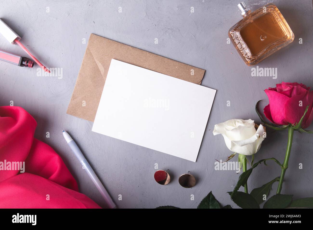 Romantic writing set with fresh roses and elegant perfume on a textured ...