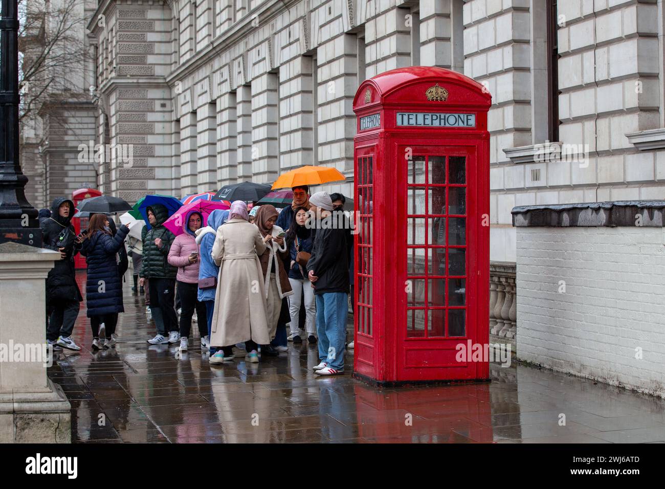 London,Uk,13th Feb 2024 Tourist queue in the rain with umbrellas to ...