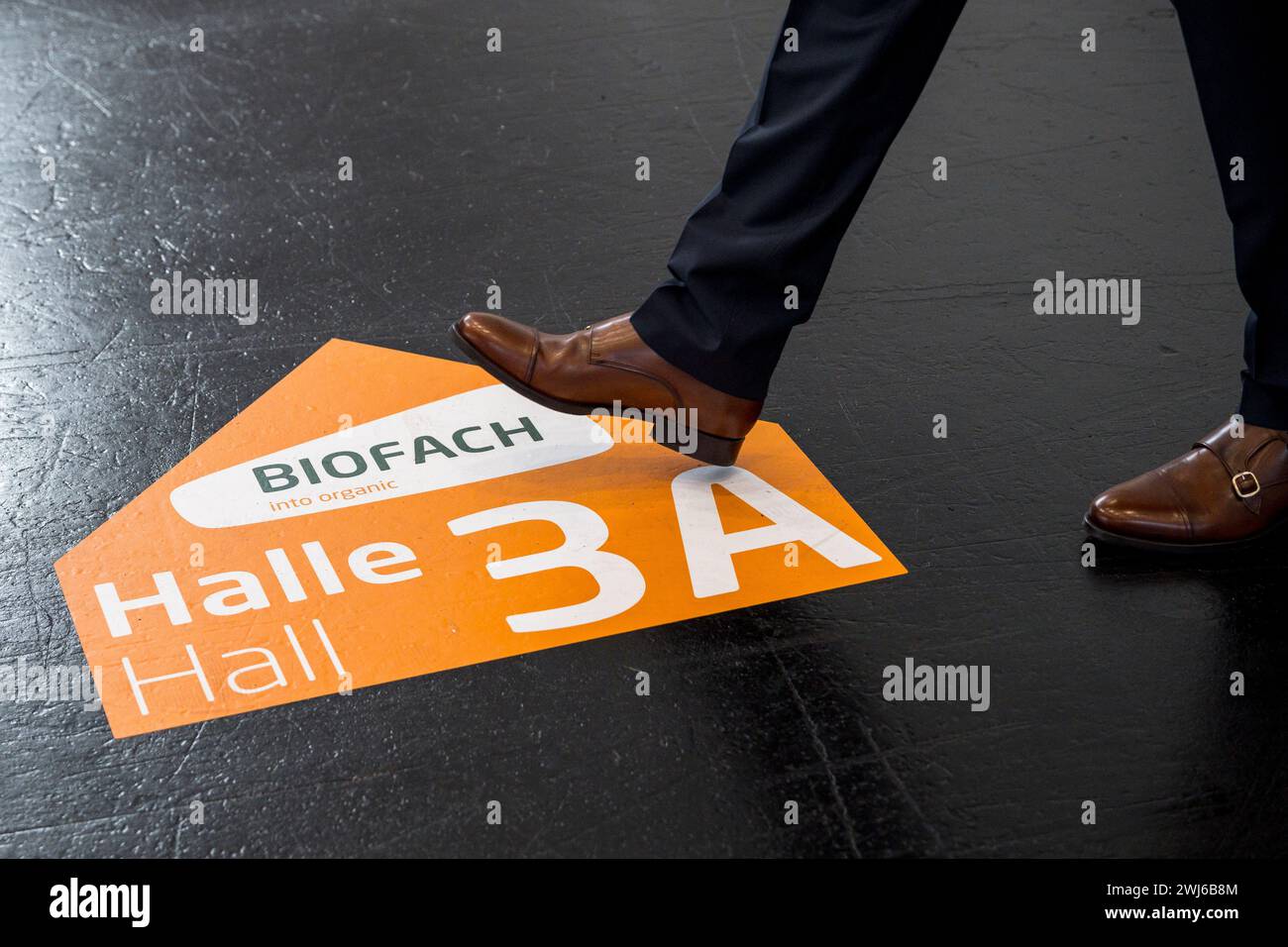 Nuremberg, Germany. 13th Feb, 2024. A man walks across the Biofach logo ...