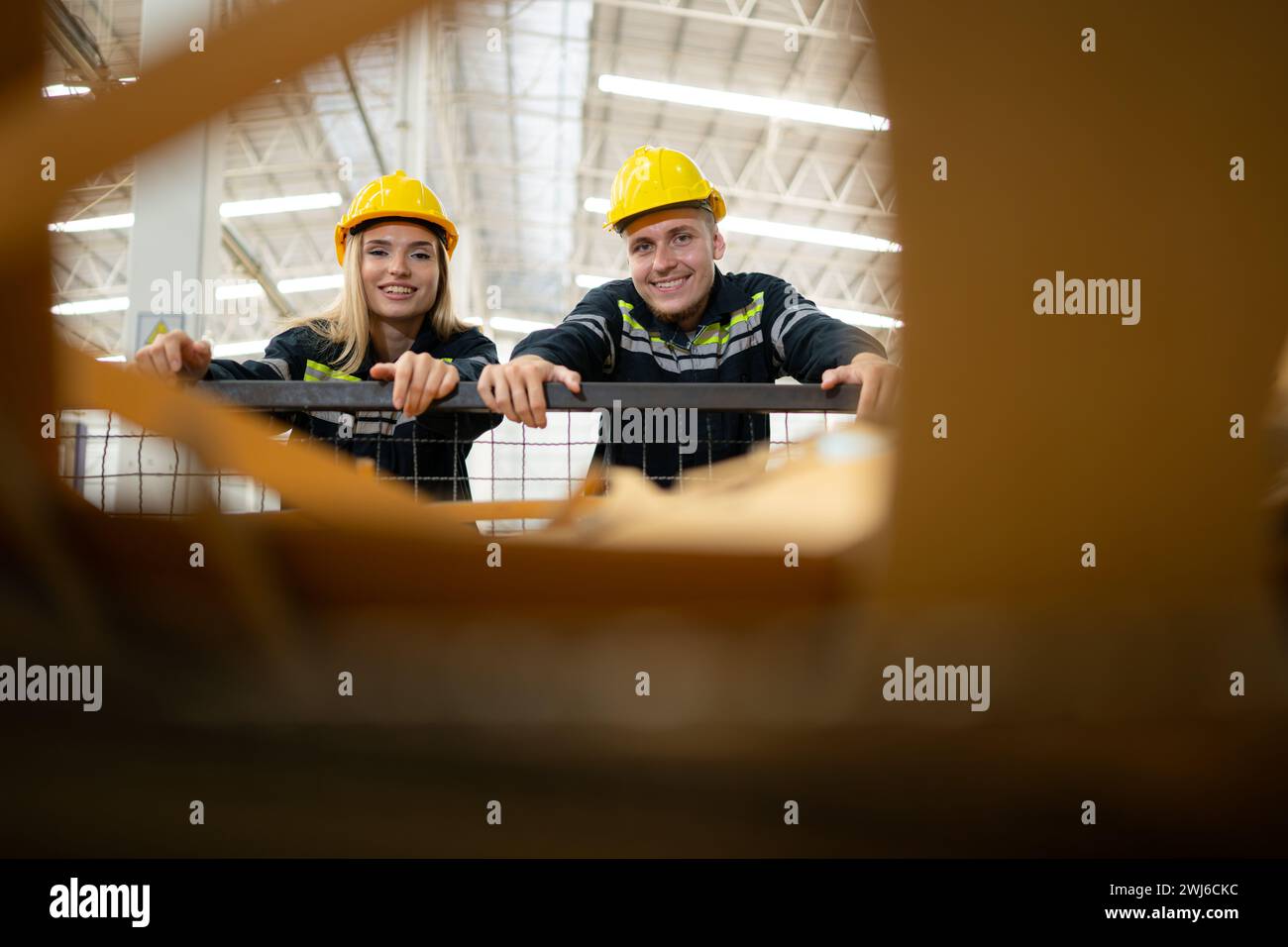 Two factory workers work in a warehouse, pushing a paper cart to be ...