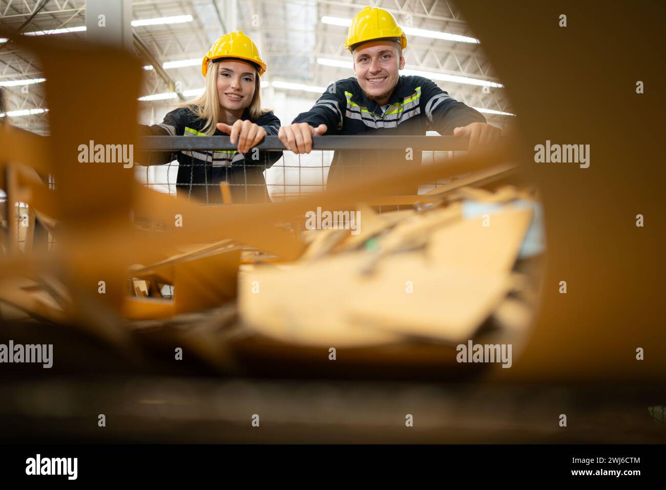 Two factory workers work in a warehouse, pushing a paper cart to be ...