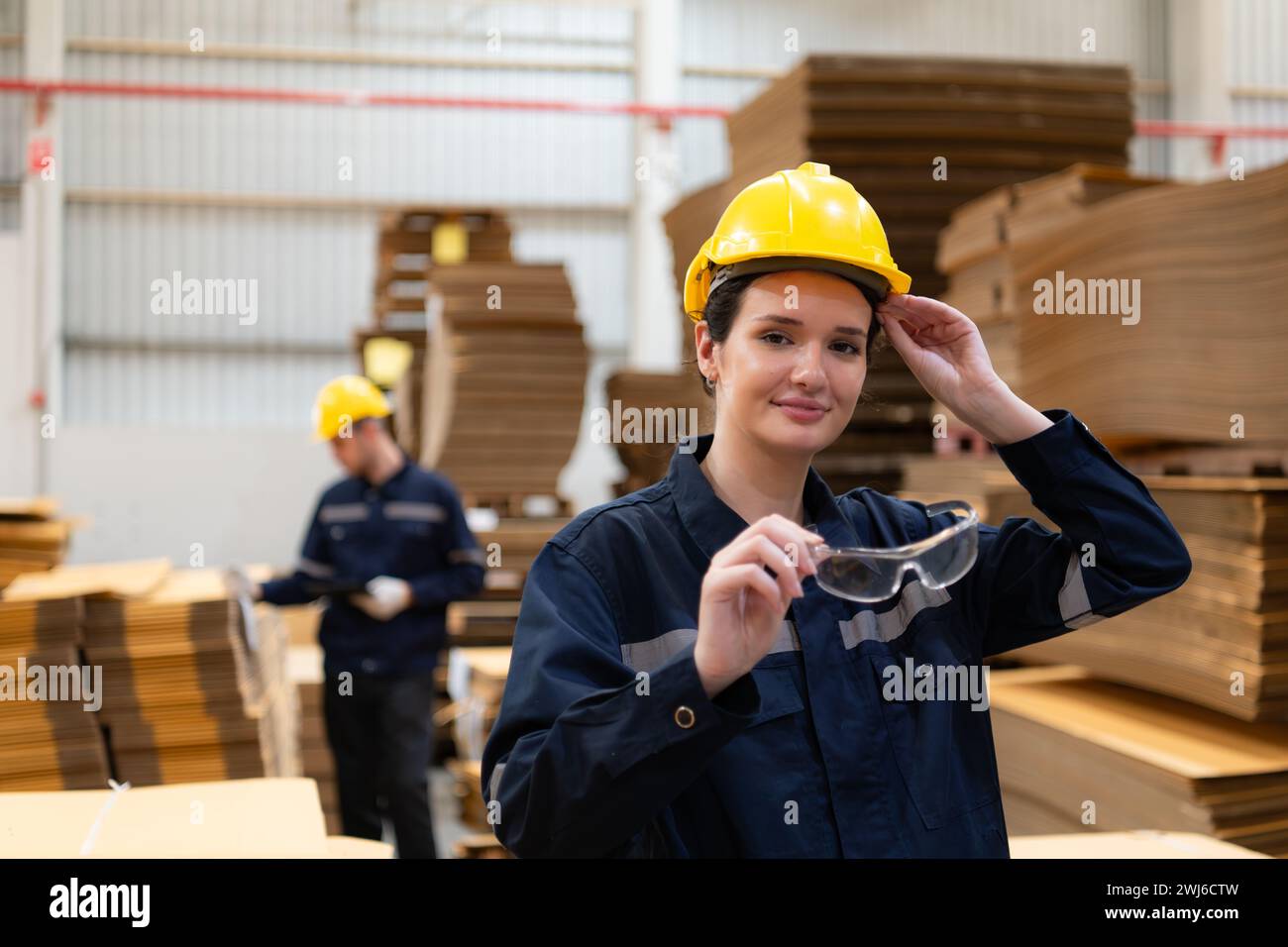 Portrait of female warehouse worker holding eyeglasses in warehouse ...