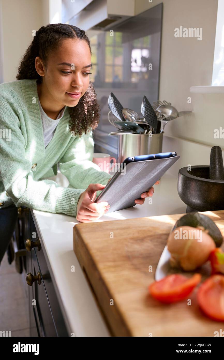 Teenage Girl At Home In Kitchen With Ingredients Looking At Recipe On ...