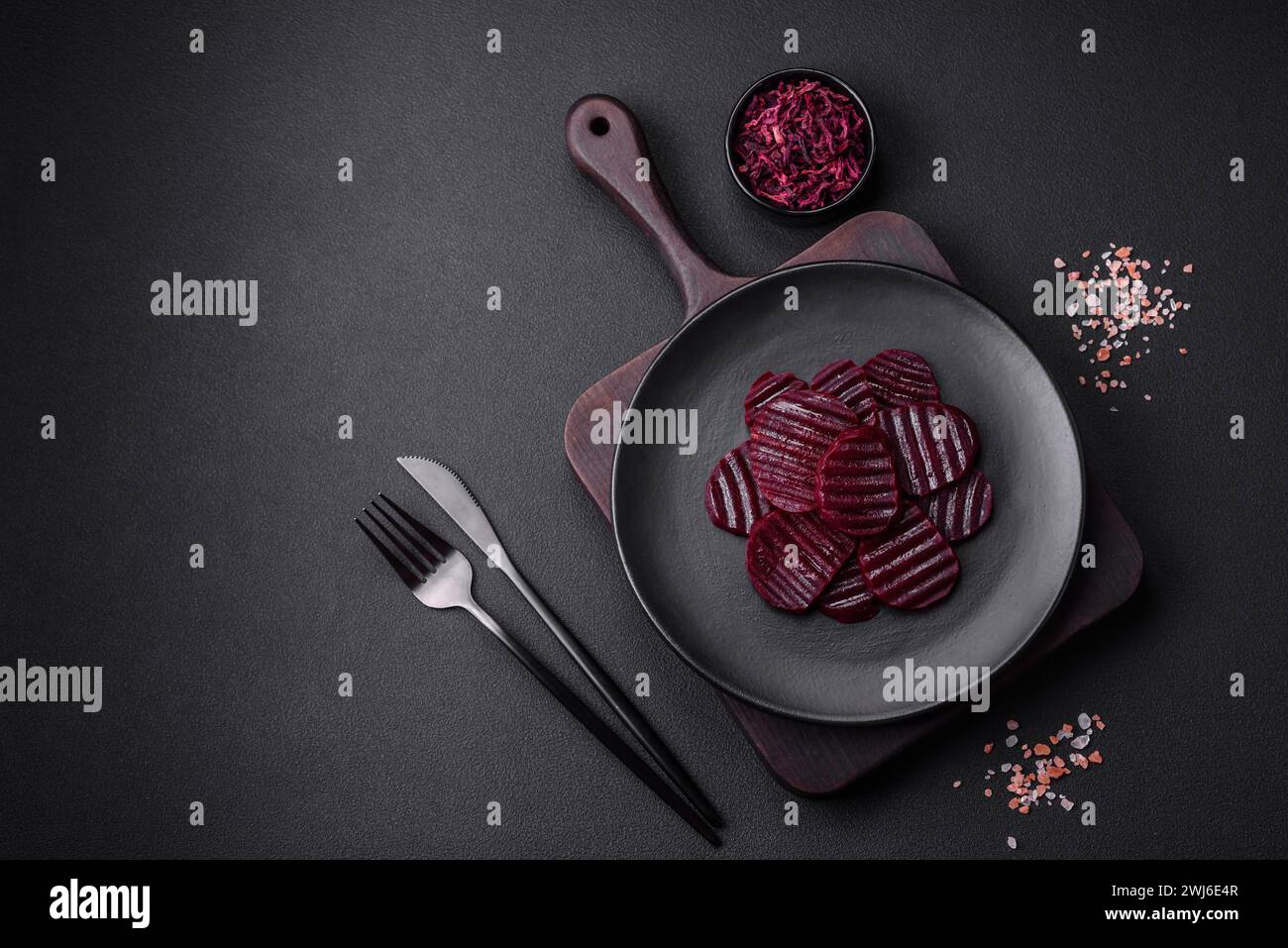 Delicious healthy boiled ruby-colored beets sliced ??on a black plate ...