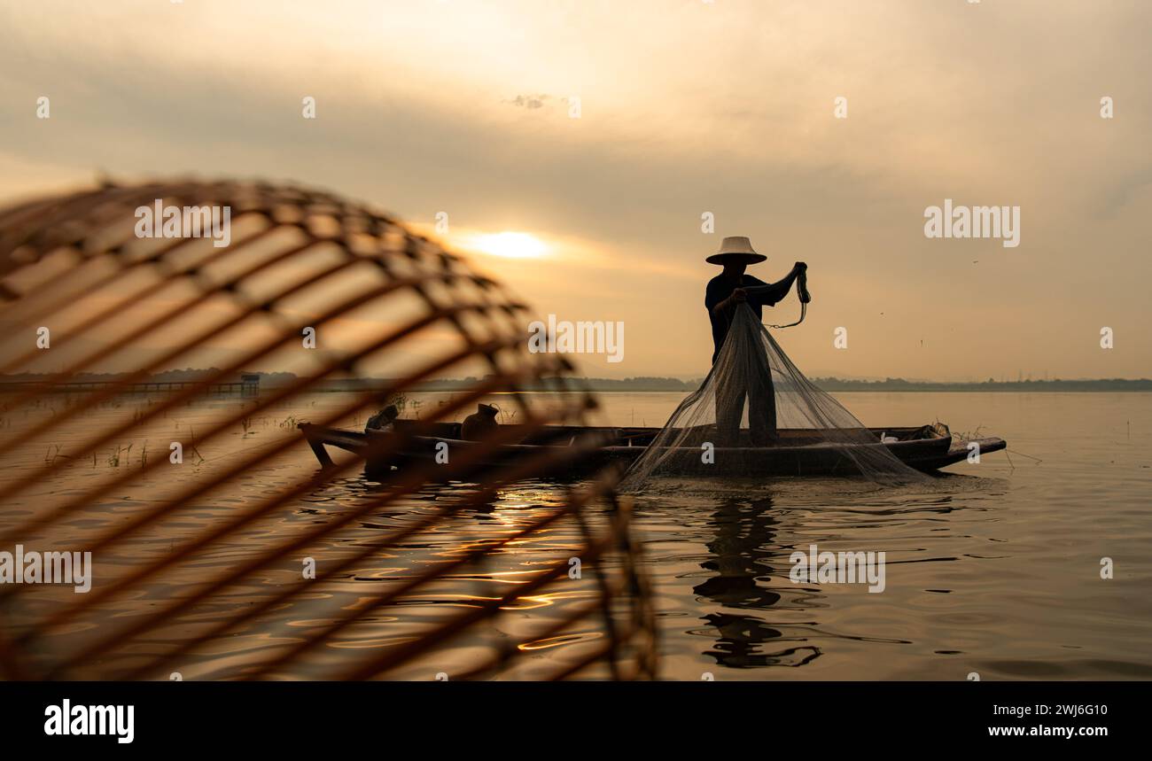 Silhouette of fisherman at sunrise, Standing aboard a rowing boat and ...