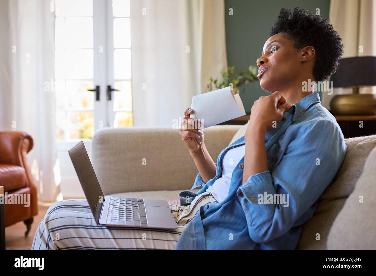 Menopausal Mature Woman At Home With Laptop Having Hot Flush Fanning ...