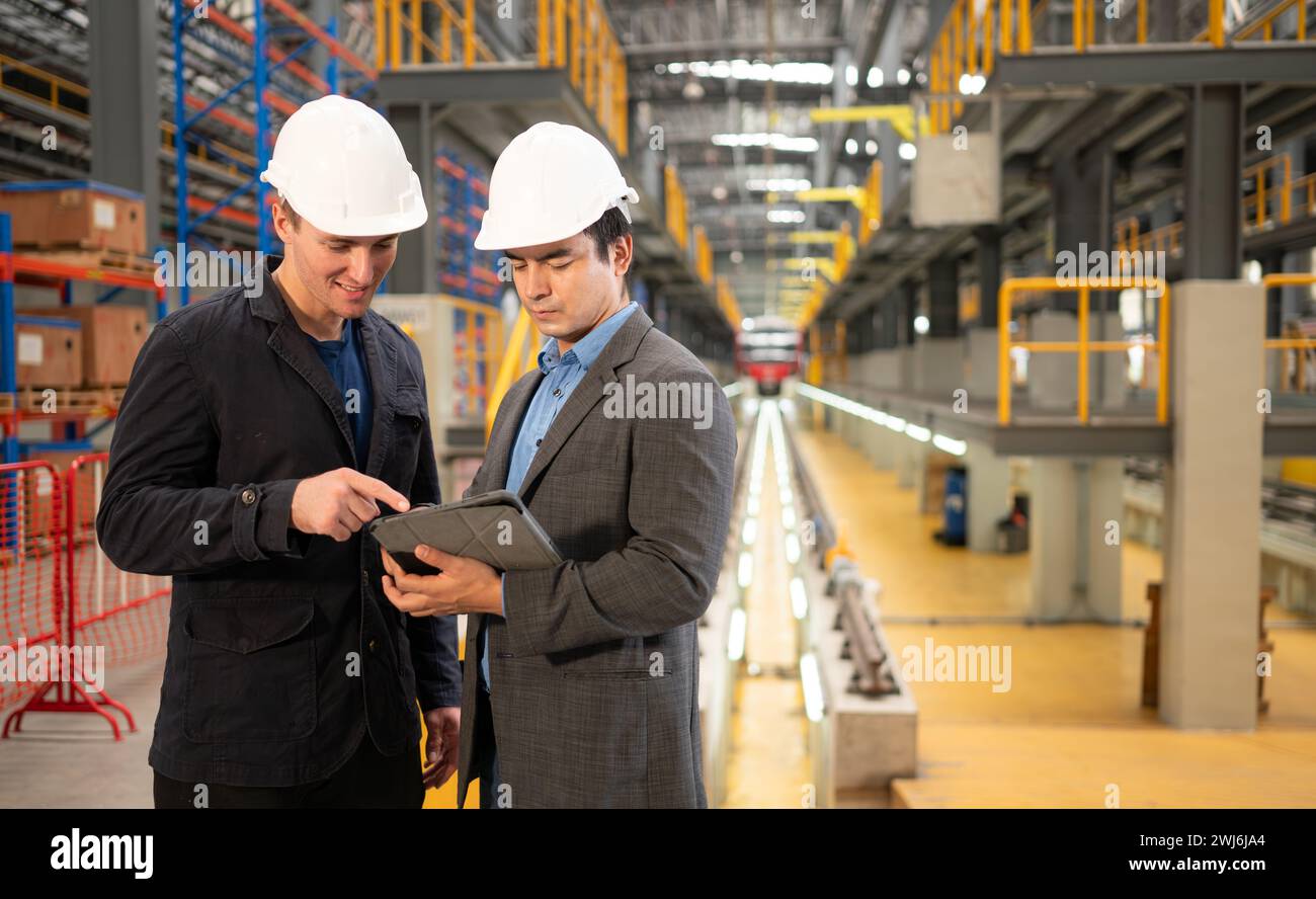 Two businessmen inspect the electric train system using a tablet to ...