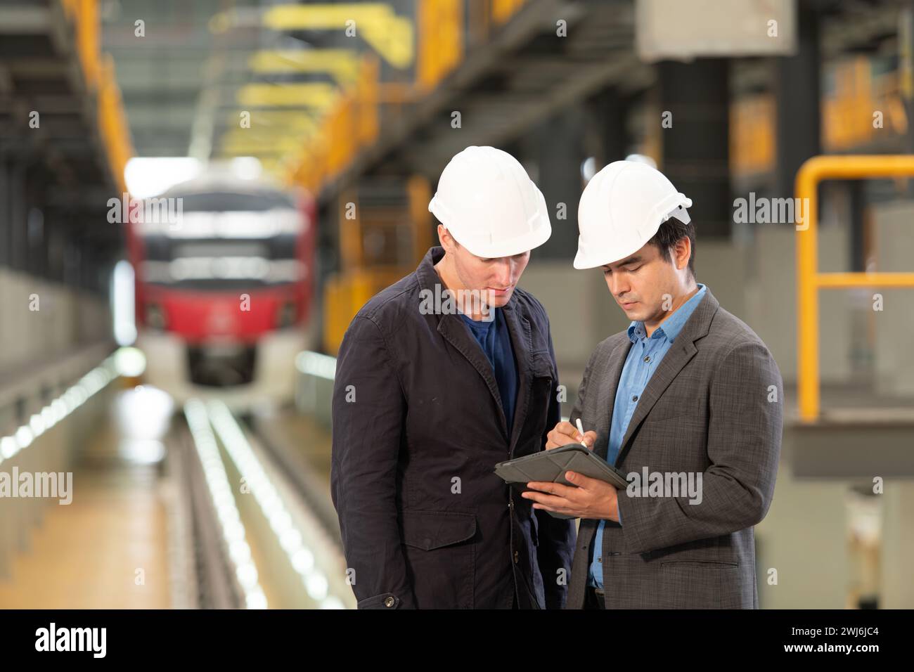 Two businessmen inspect the electric train system using a tablet to ...