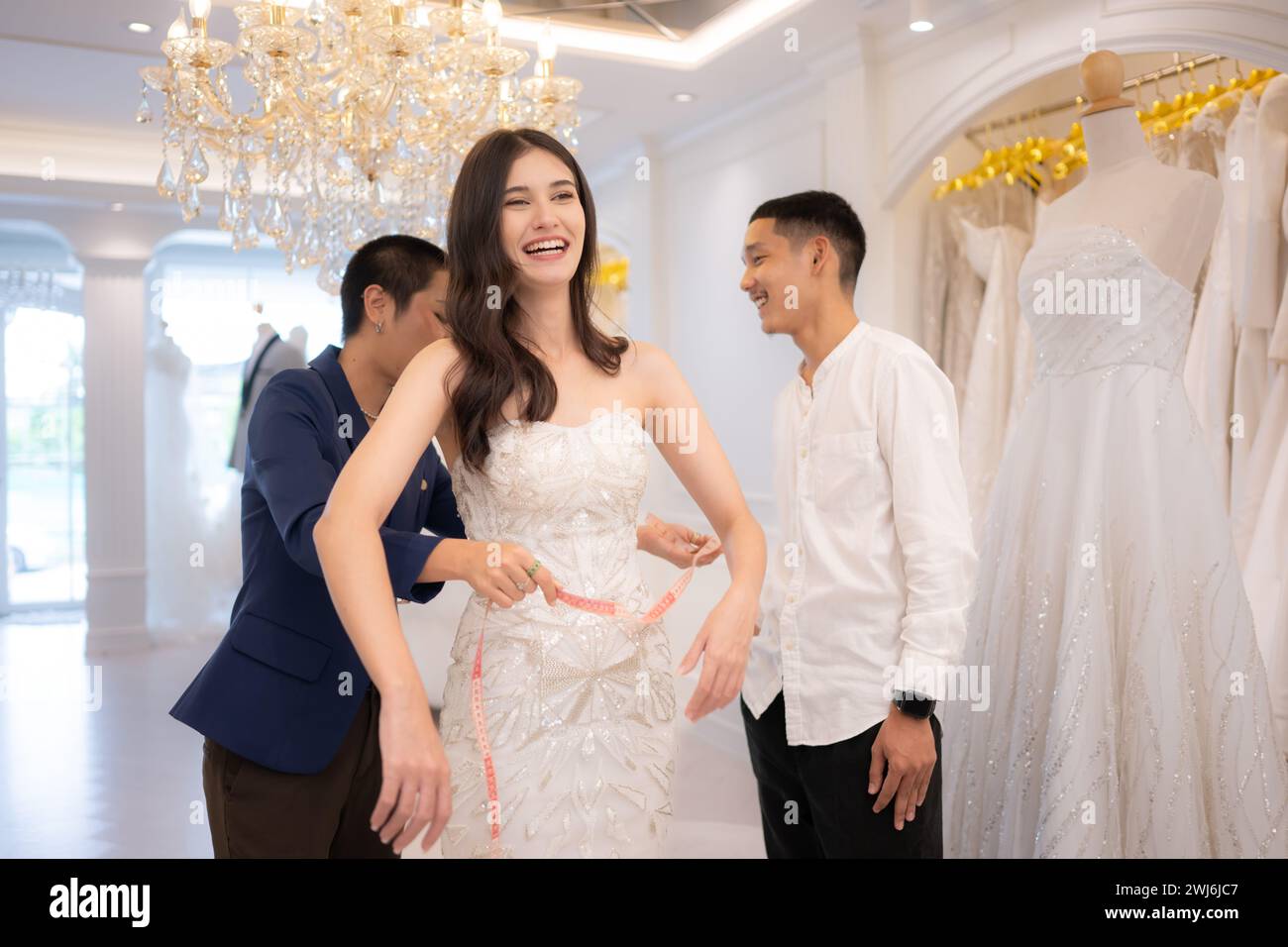 Bridal gown designers and tailors measure the size of the gown against ...