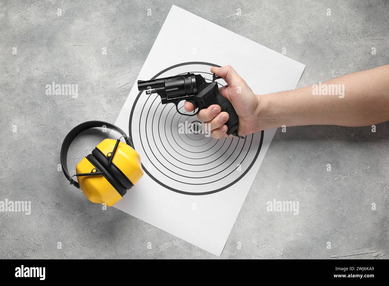 Man with handgun, shooting target and bullets at gray table, top view ...