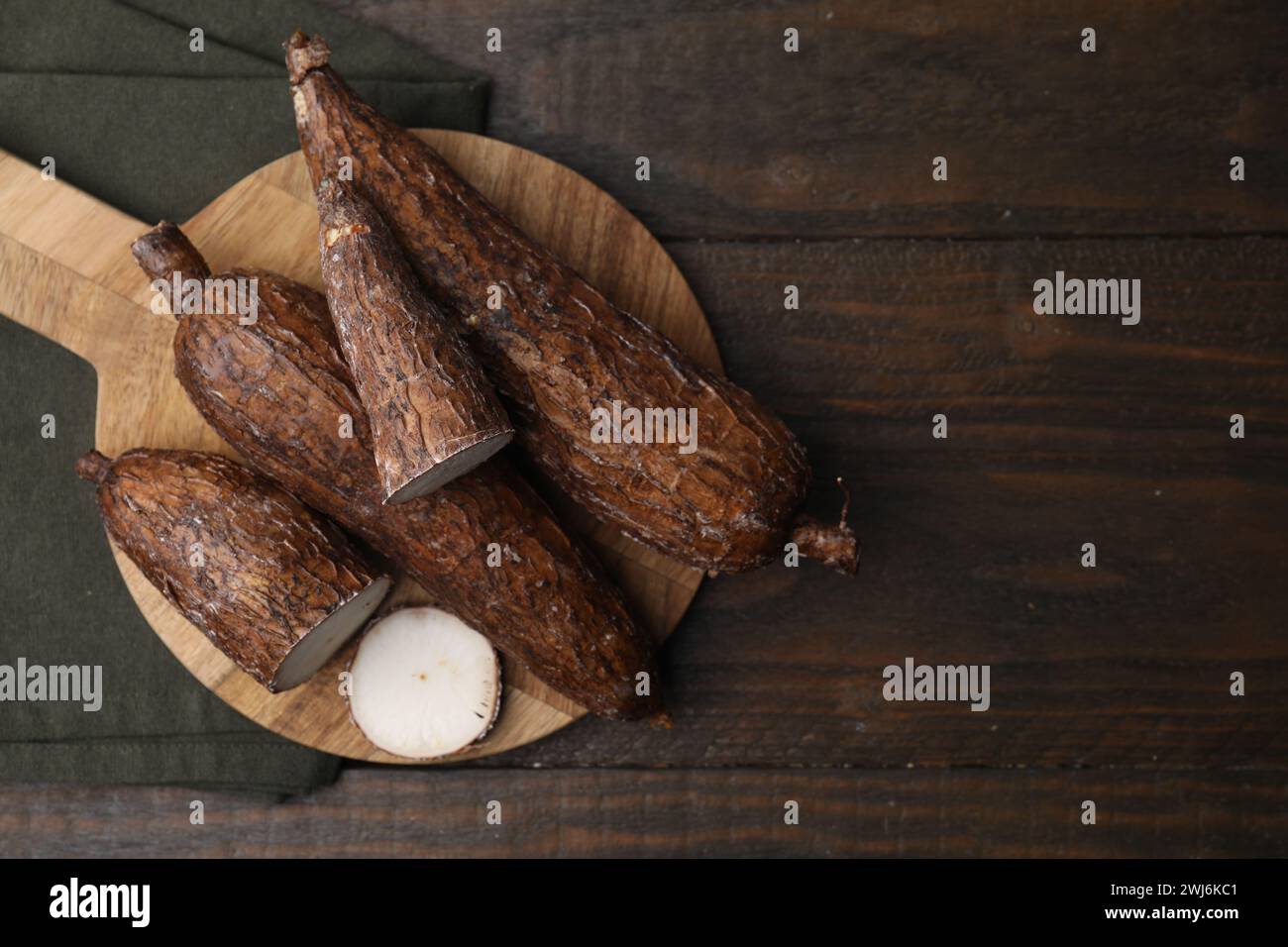 Whole and cut cassava roots on wooden table, top view. Space for text ...