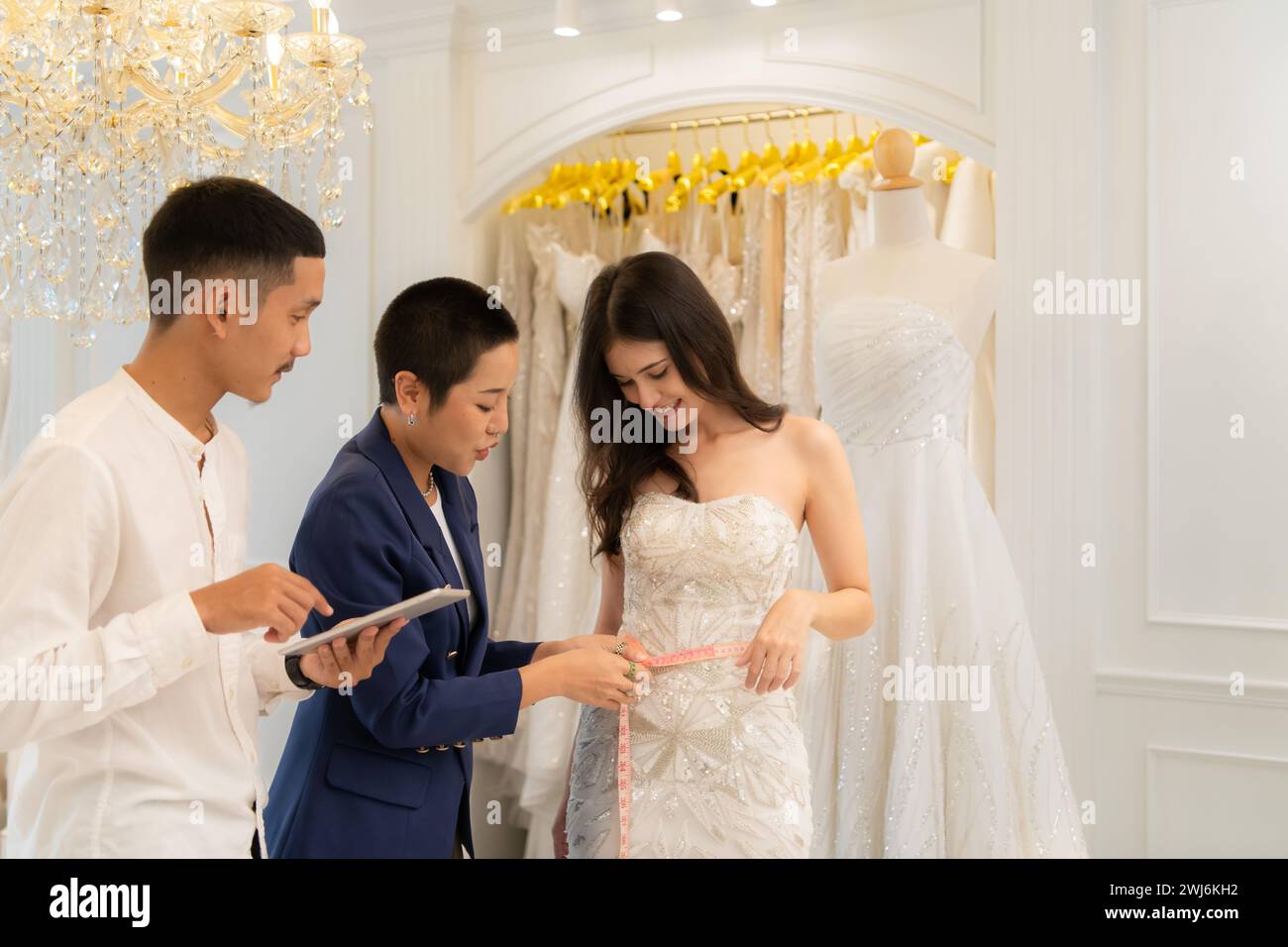Bridal gown designers and tailors measure the size of the gown against ...