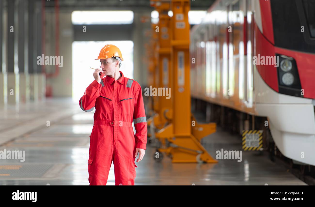 Portrait of a technician using a walkie talkie in front of a train for ...