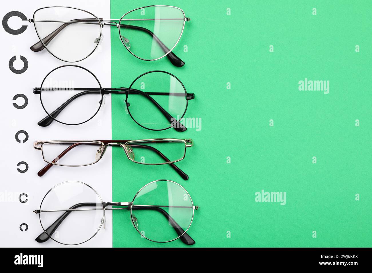 Vision test chart and glasses on green background, flat lay. Space for ...