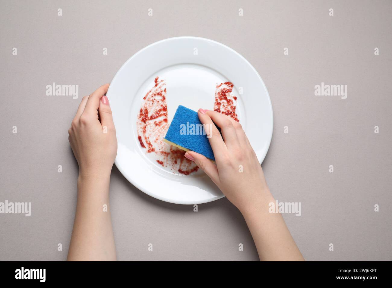 Woman washing dirty plate with sponge on light grey background, top ...