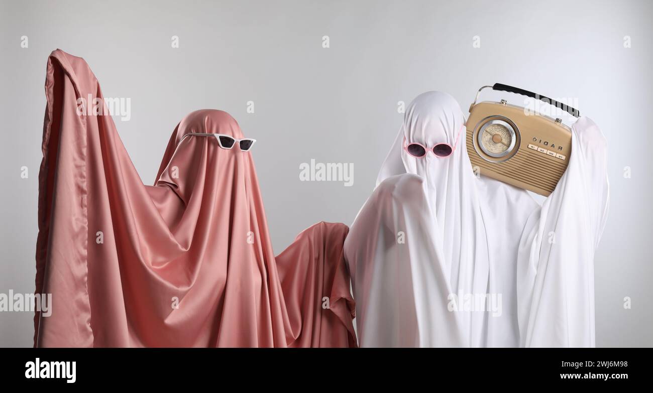Glamorous ghosts. Women in color sheets and sunglasses with retro radio ...