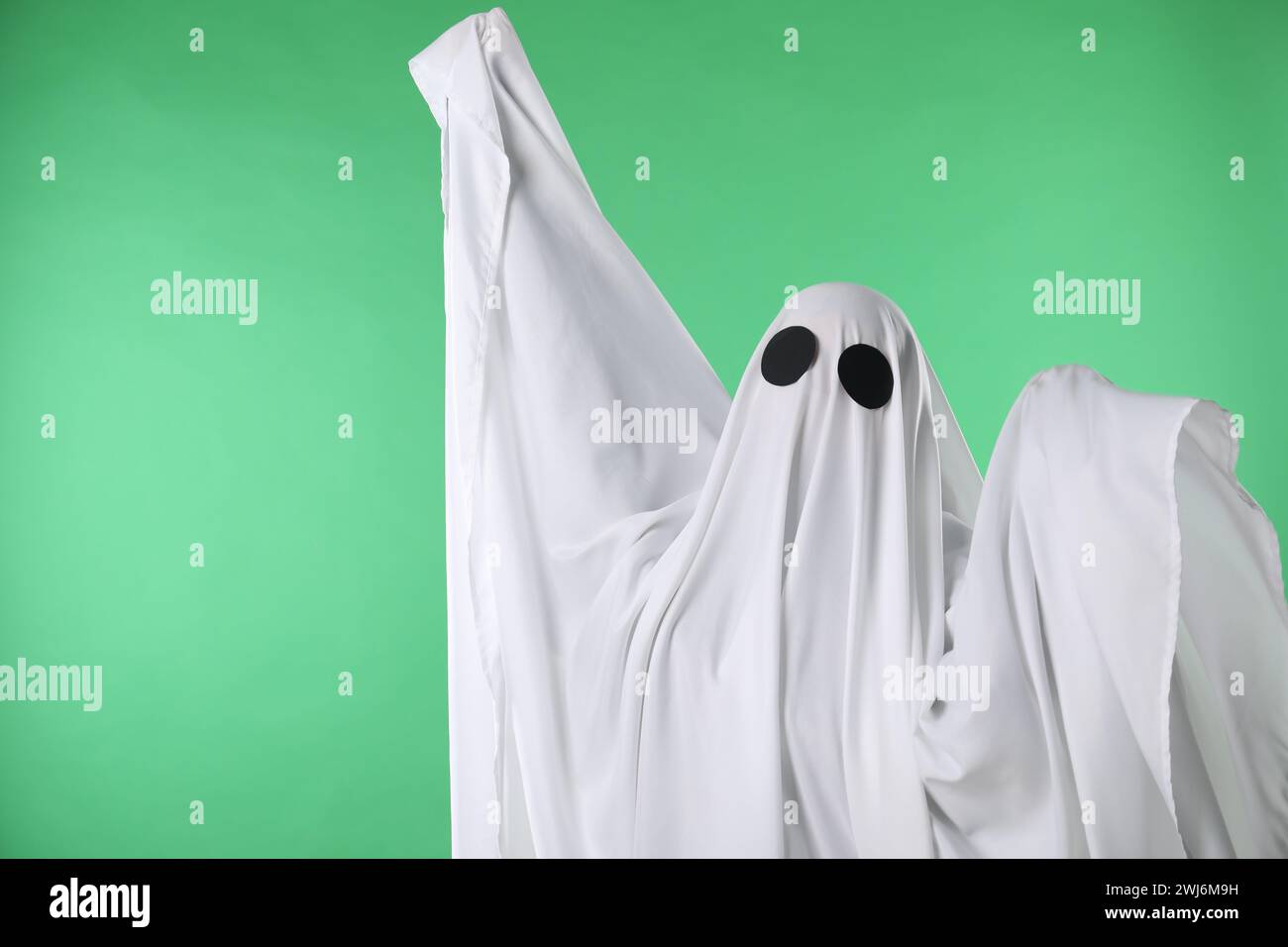 Creepy ghost. Person covered with white sheet on green background ...