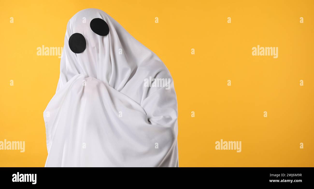 Creepy ghost. Person covered with white sheet on yellow background ...