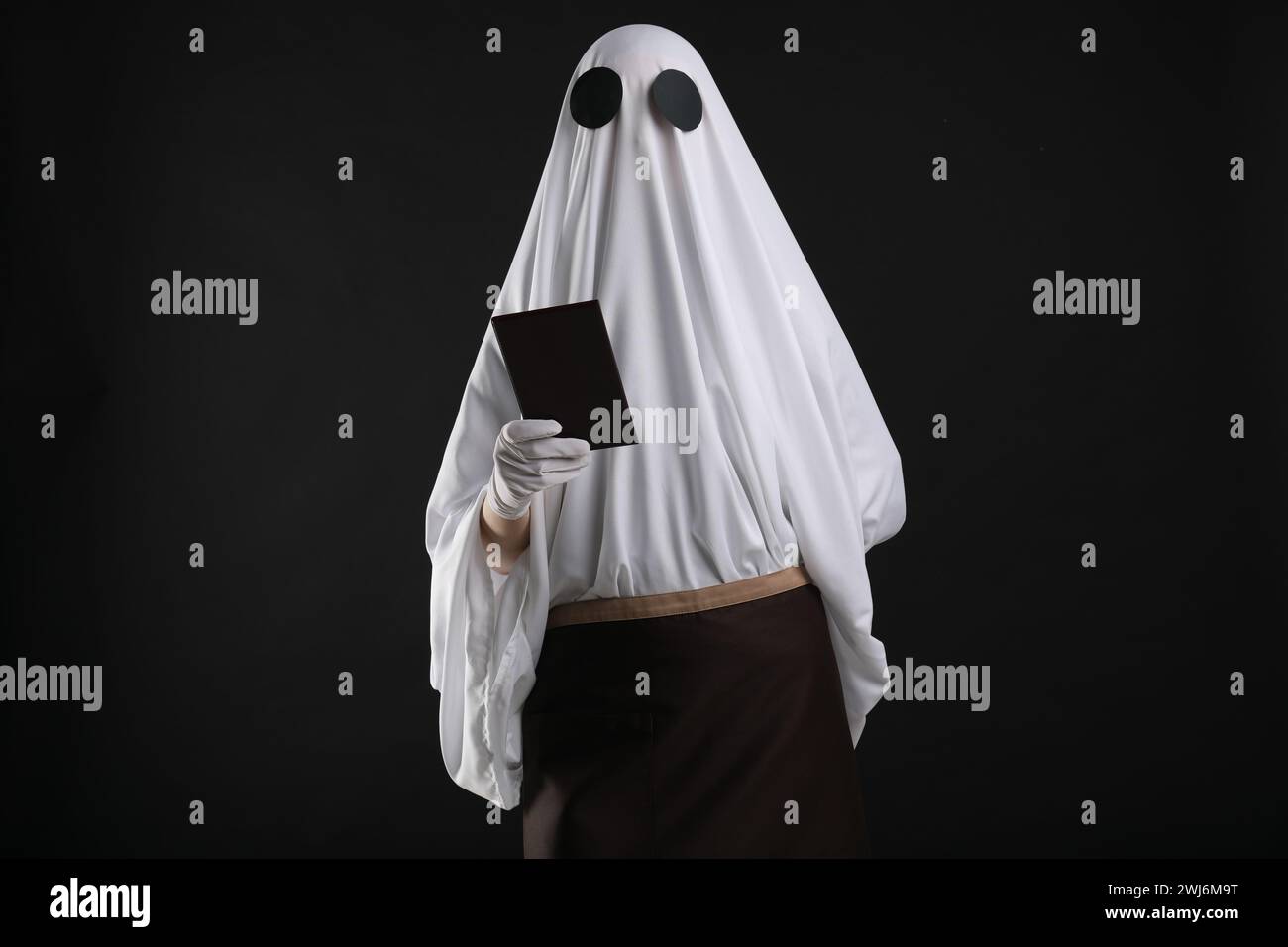 Creepy ghost. Waiter in white sheet and apron with receipt on black ...