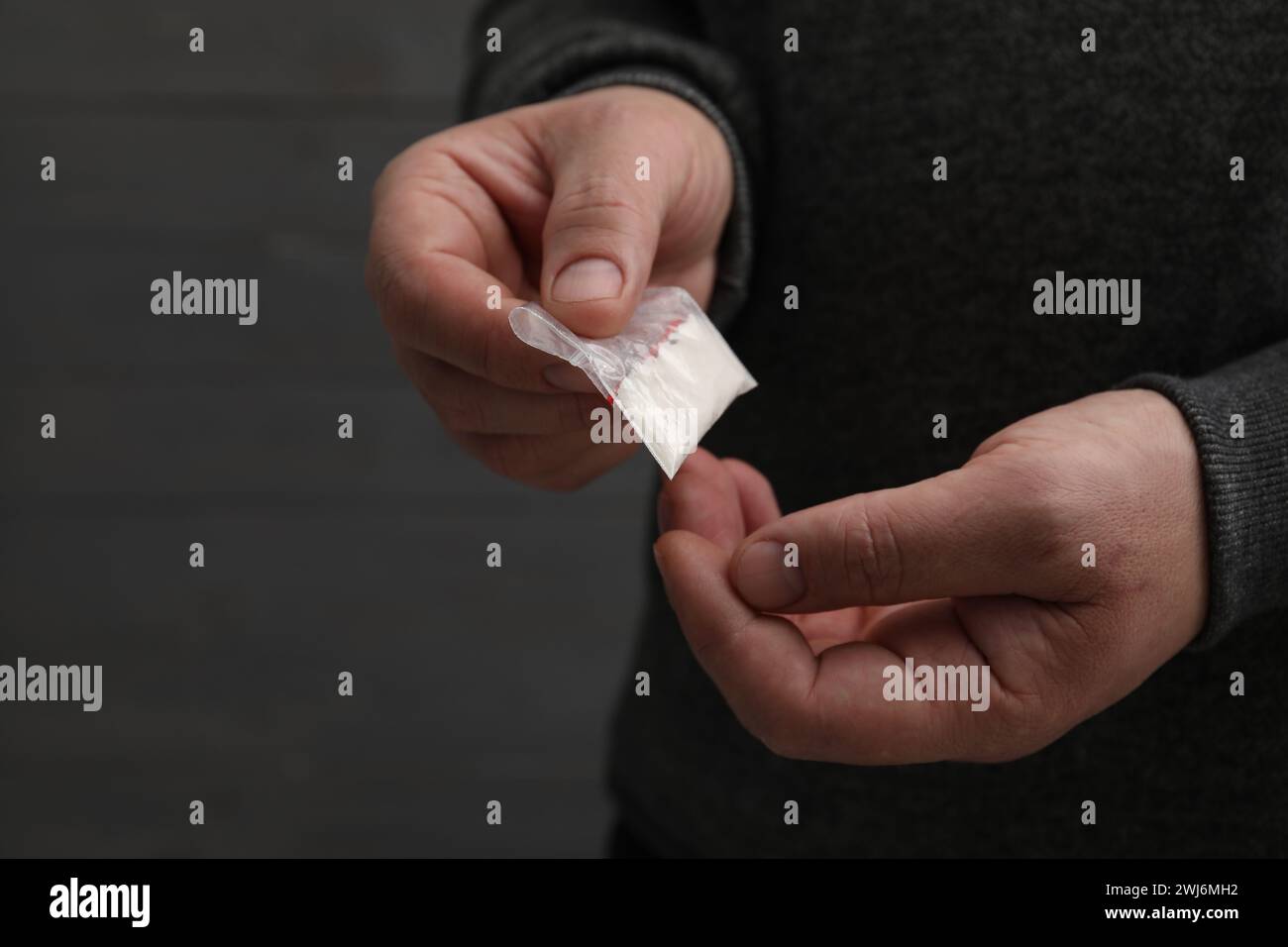 Addicted man with plastic bag of hard drug on grey background, closeup ...