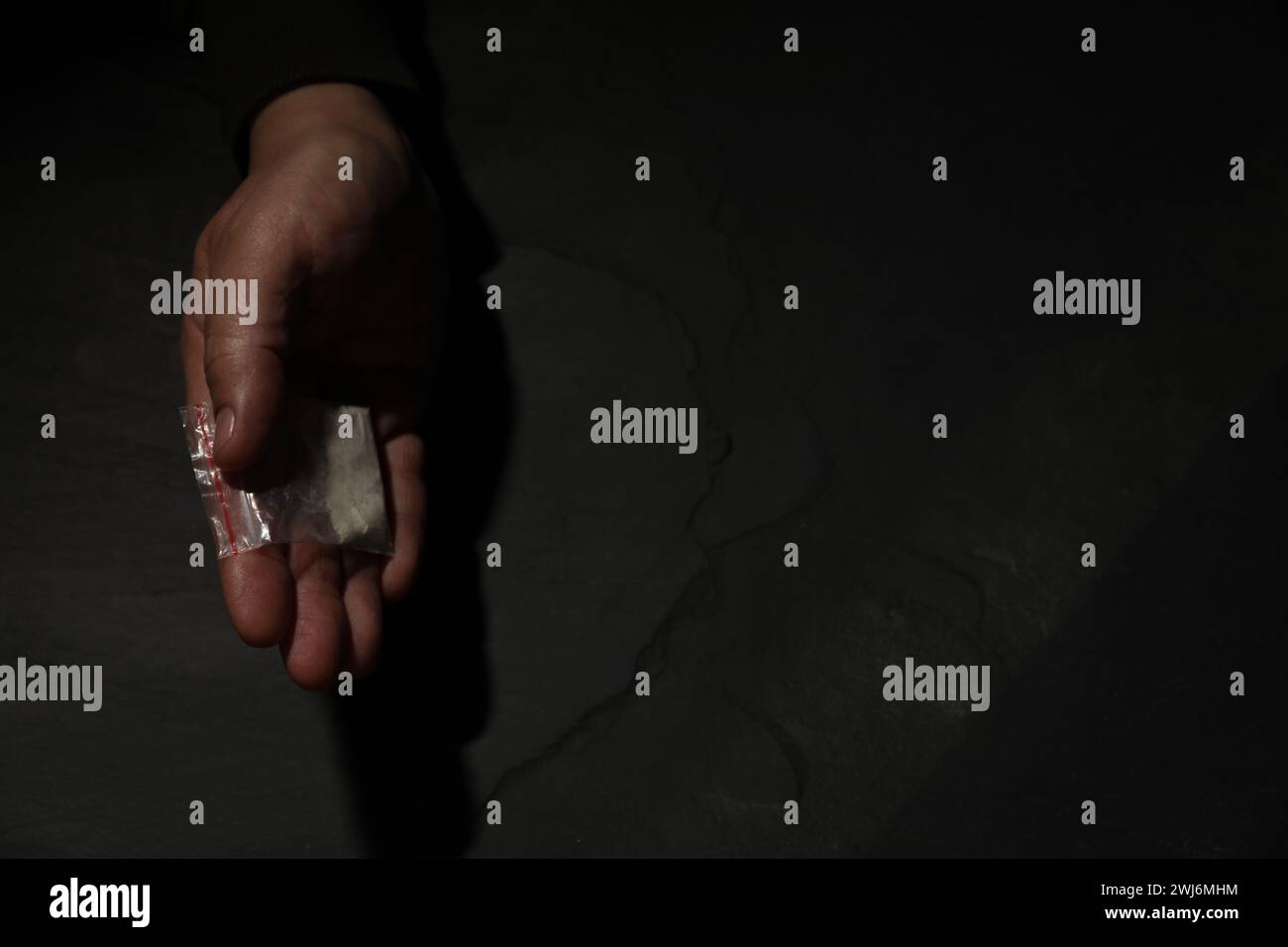 Addicted man with plastic bag of hard drug at grey textured table, top ...