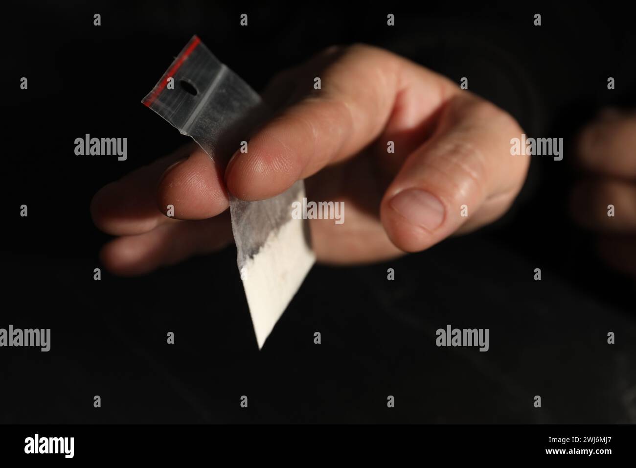 Drug addiction. Man with plastic bag of cocaine on dark background ...