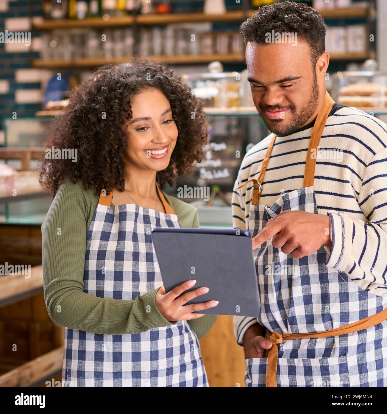 Woman Using Digital Tablet Working In Food Shop Training Man With Down ...