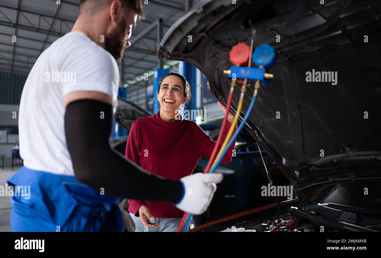 Car mechanic working in an auto repair shop explain to customer after inspecting the operation ...