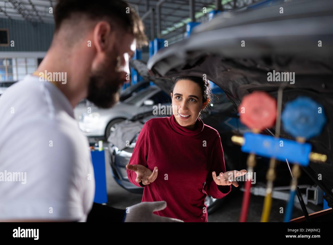 Car mechanic working in an auto repair shop explain to customer after ...