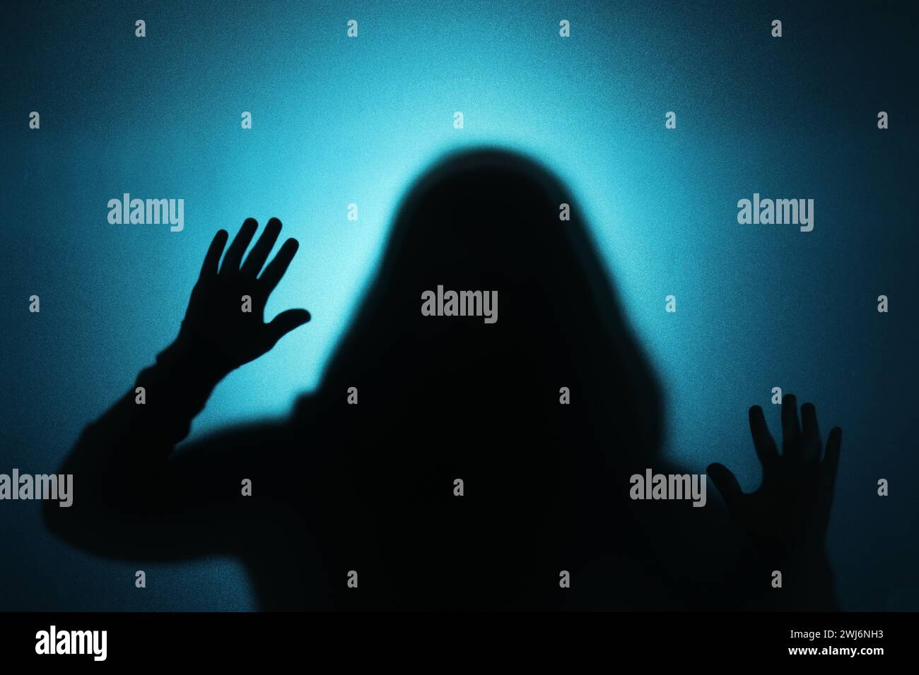 Silhouette of ghost behind glass against blue background Stock Photo ...