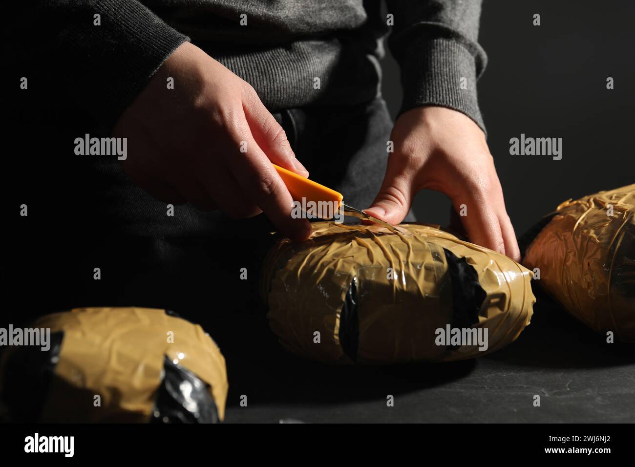 Smuggling and drug trafficking. Man opening package of narcotics with ...