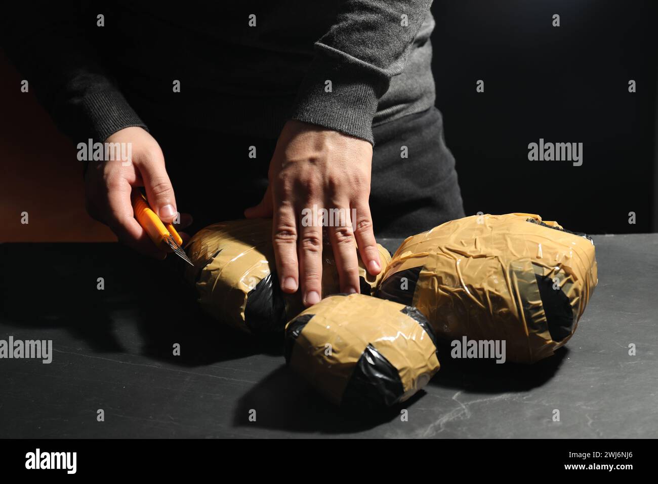 Smuggling and drug trafficking. Man opening package of narcotics with ...