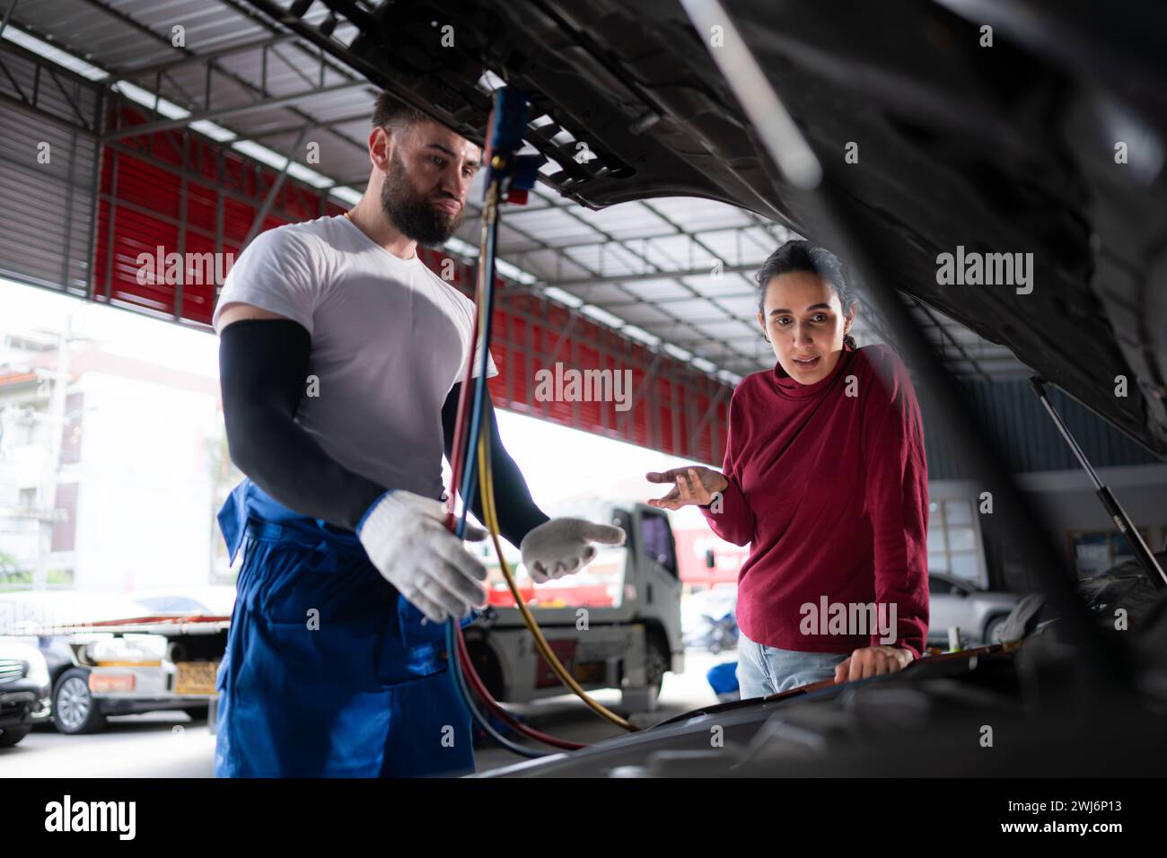 Car mechanic working in an auto repair shop explain to customer after ...