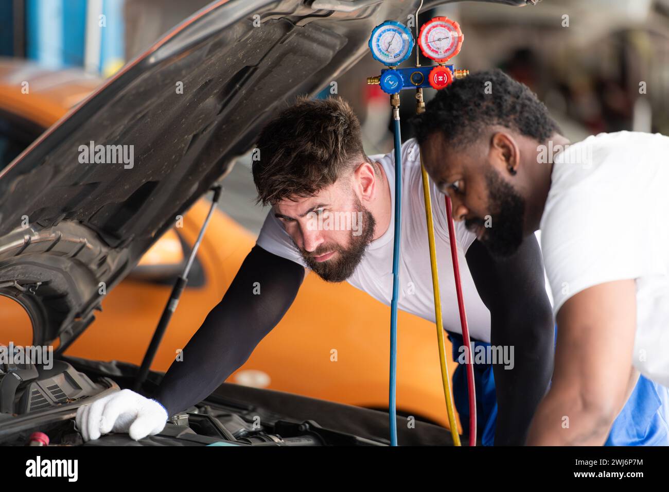 Car mechanic working in an auto repair shop, inspecting the operation of the car's air ...