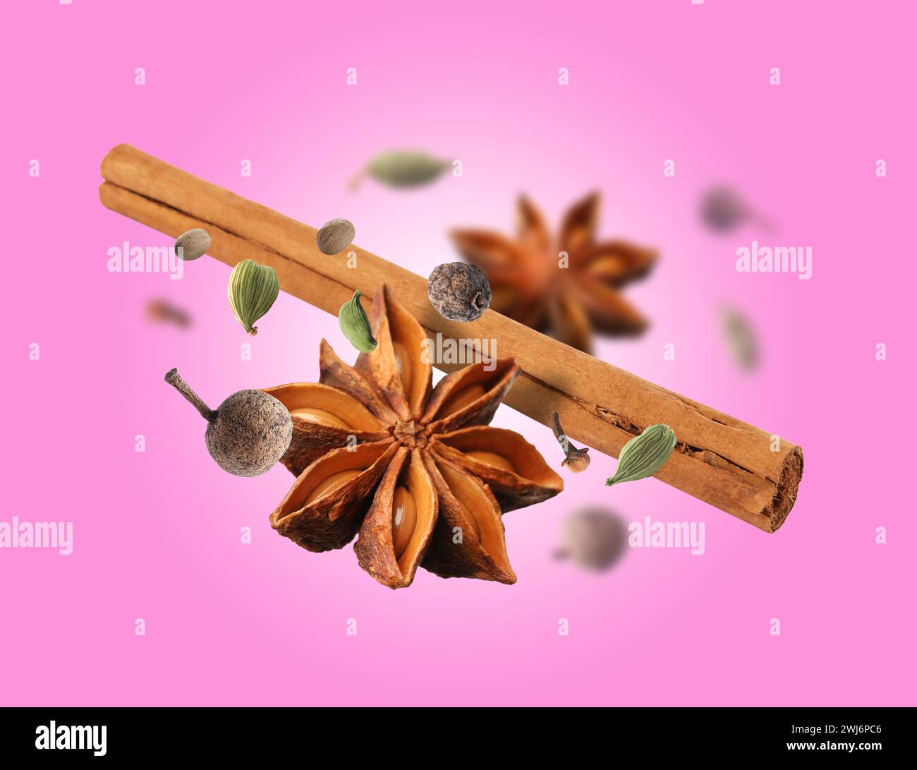 Different aromatic spices falling on pink background Stock Photo - Alamy