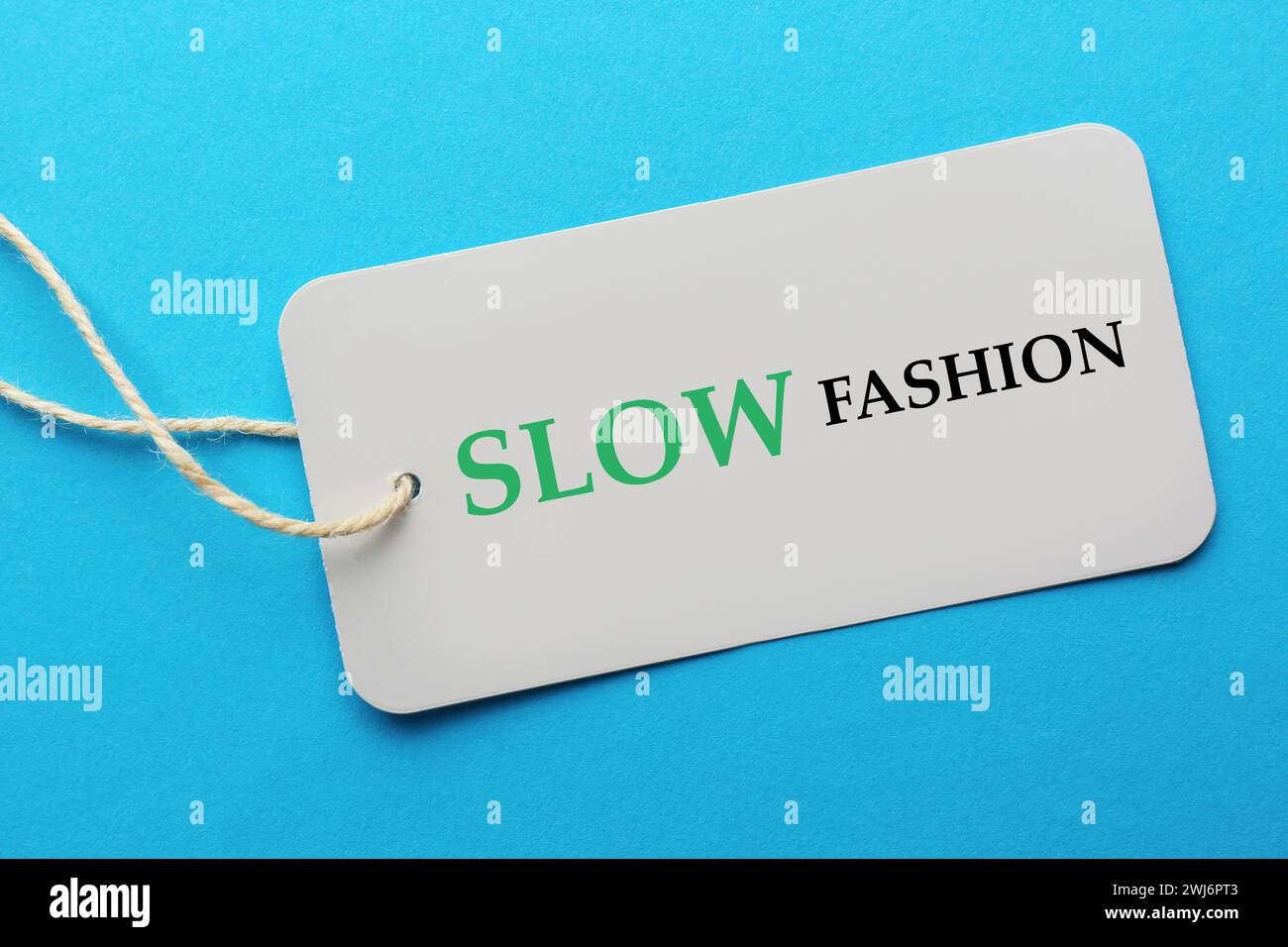 Conscious consumption. Tag with words Slow Fashion on light blue ...