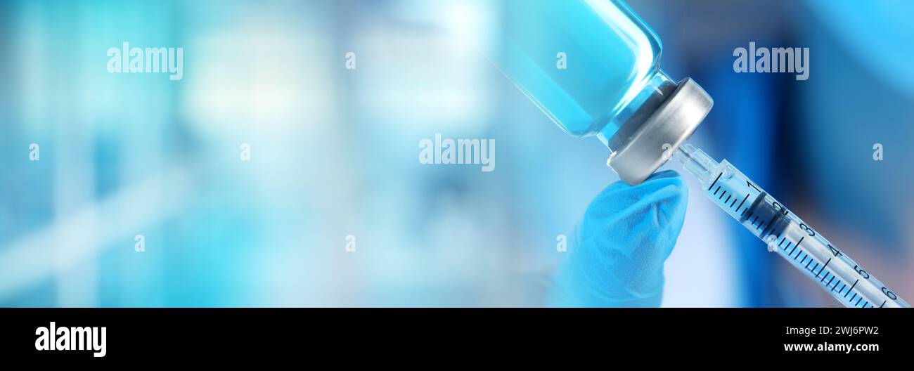 Doctor filling syringe with medication from glass vial on blurred ...