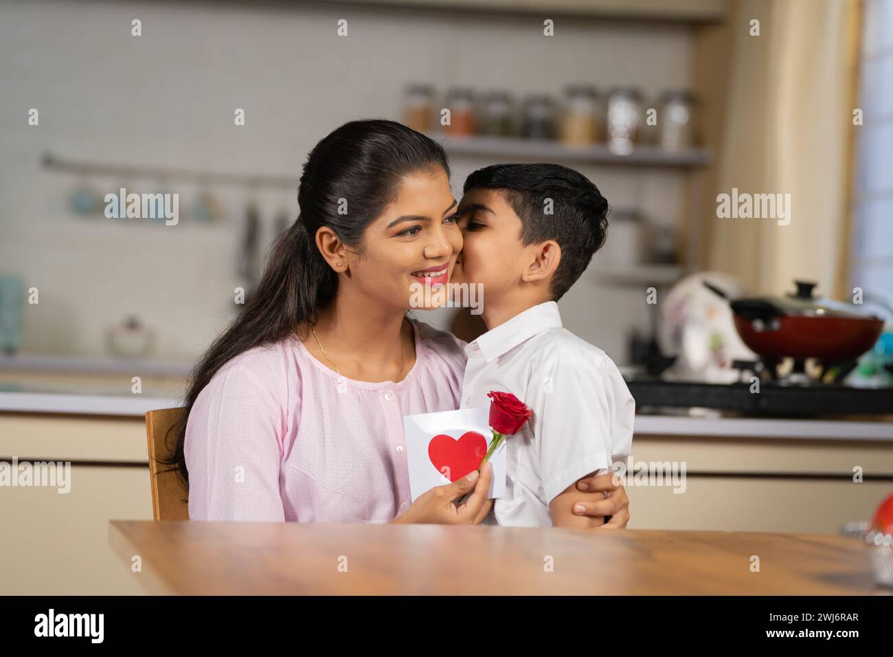 Loving son giving mother day greeting card with rose to happy mother at ...