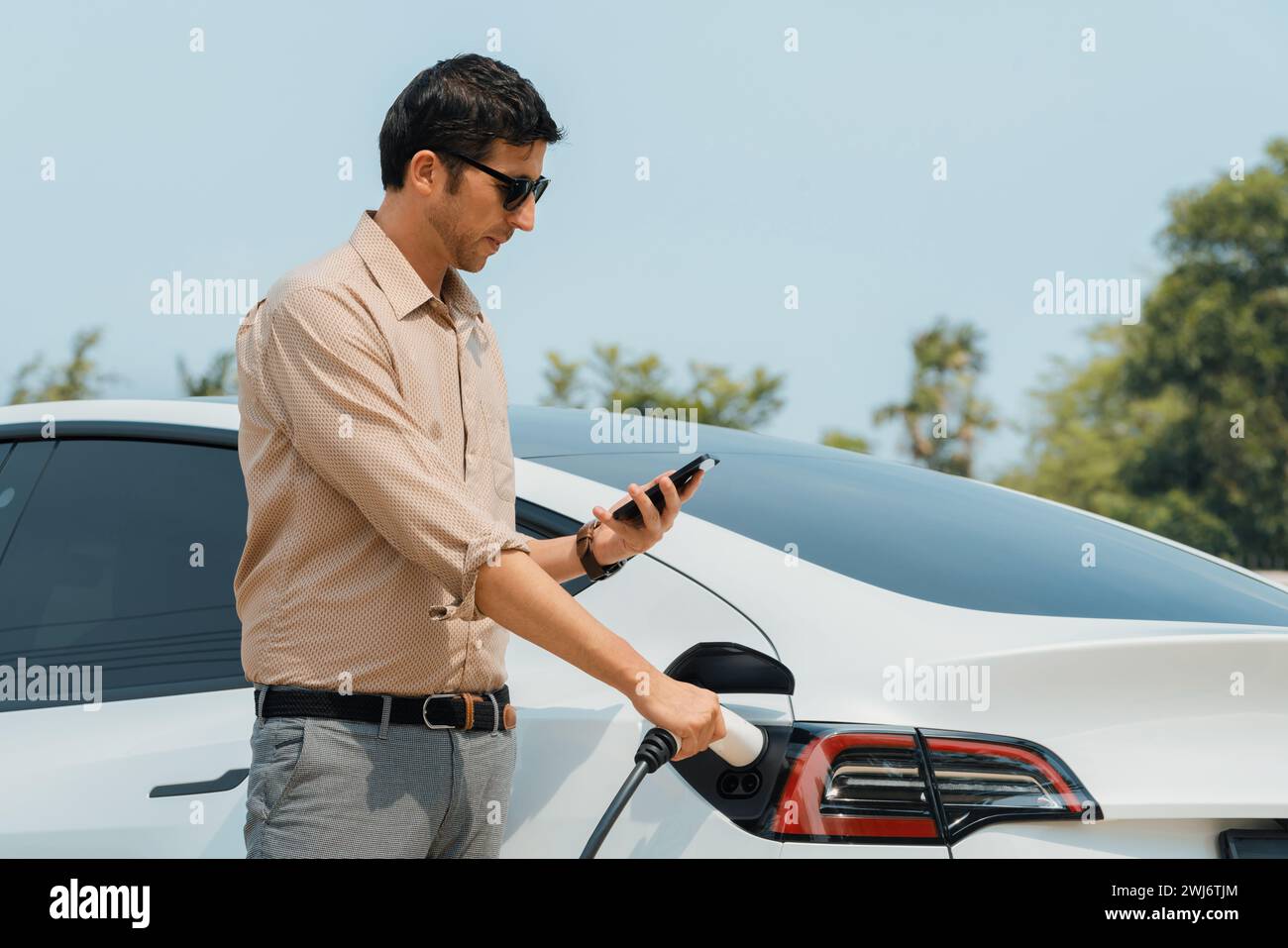 Young man use smartphone to pay for electricity at public EV car ...