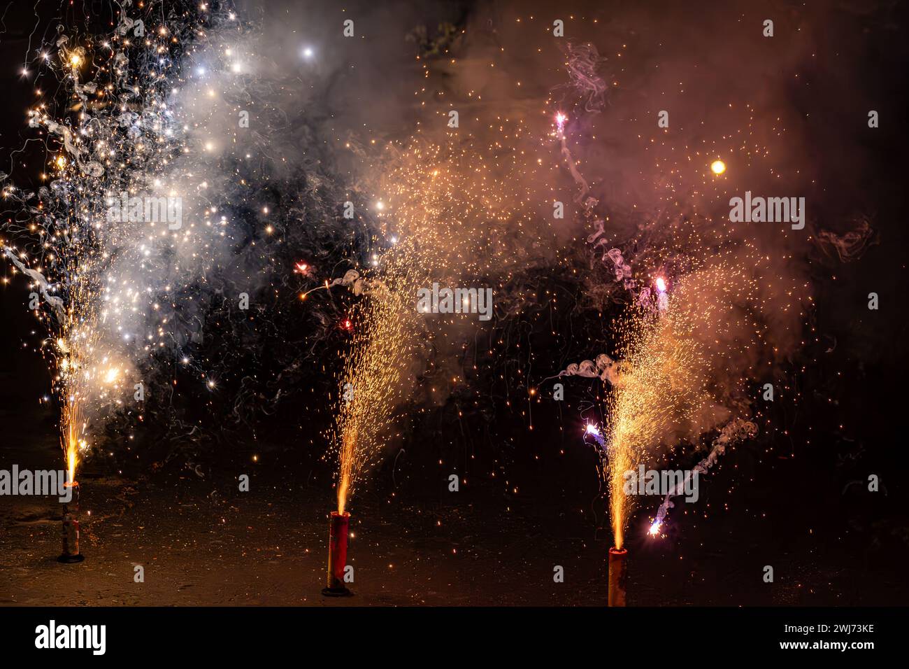 Three home fireworks sending sparks upwards Stock Photo - Alamy