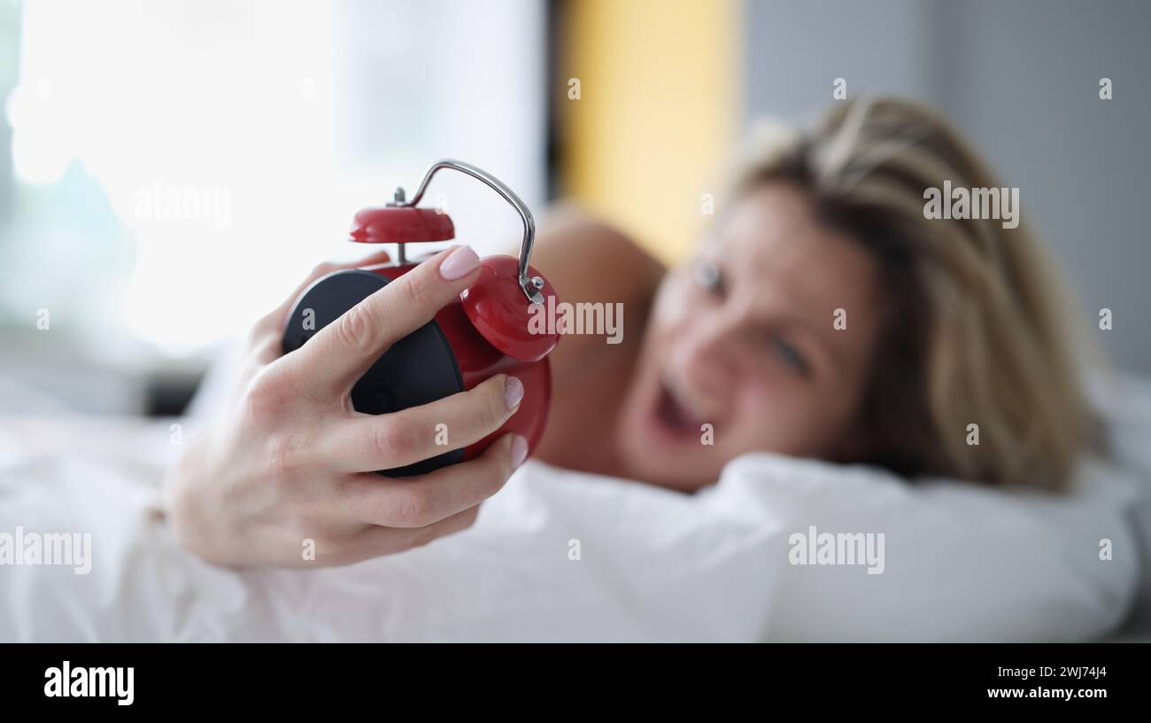 Screaming woman in bed with a red alarm clock in her hand Stock Photo ...
