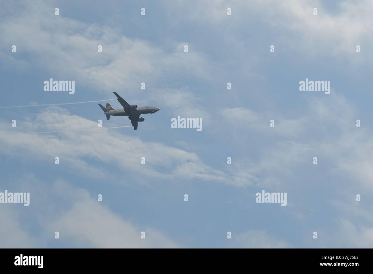 Photograph of an Airplane flying through a clouded sky with 2 trails ...