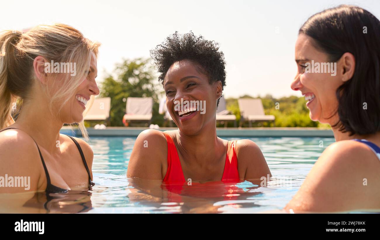 Three Mature Female Friends Wearing Swimsuits In Outdoor Pool On Spa ...