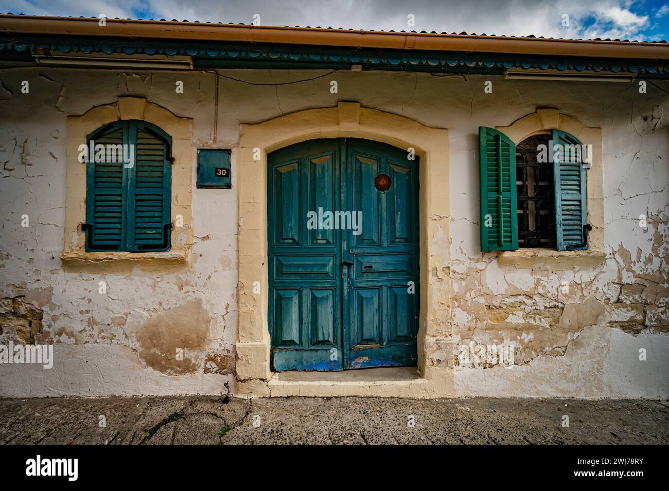 An aged house featuring a weathered blue door is captured in a vintage ...