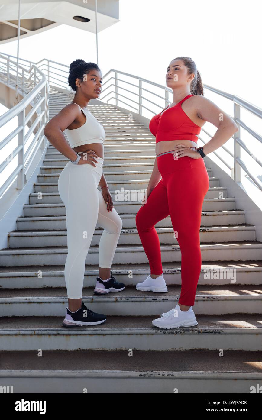 Full length of two plus size females wearing sportswear with different ...