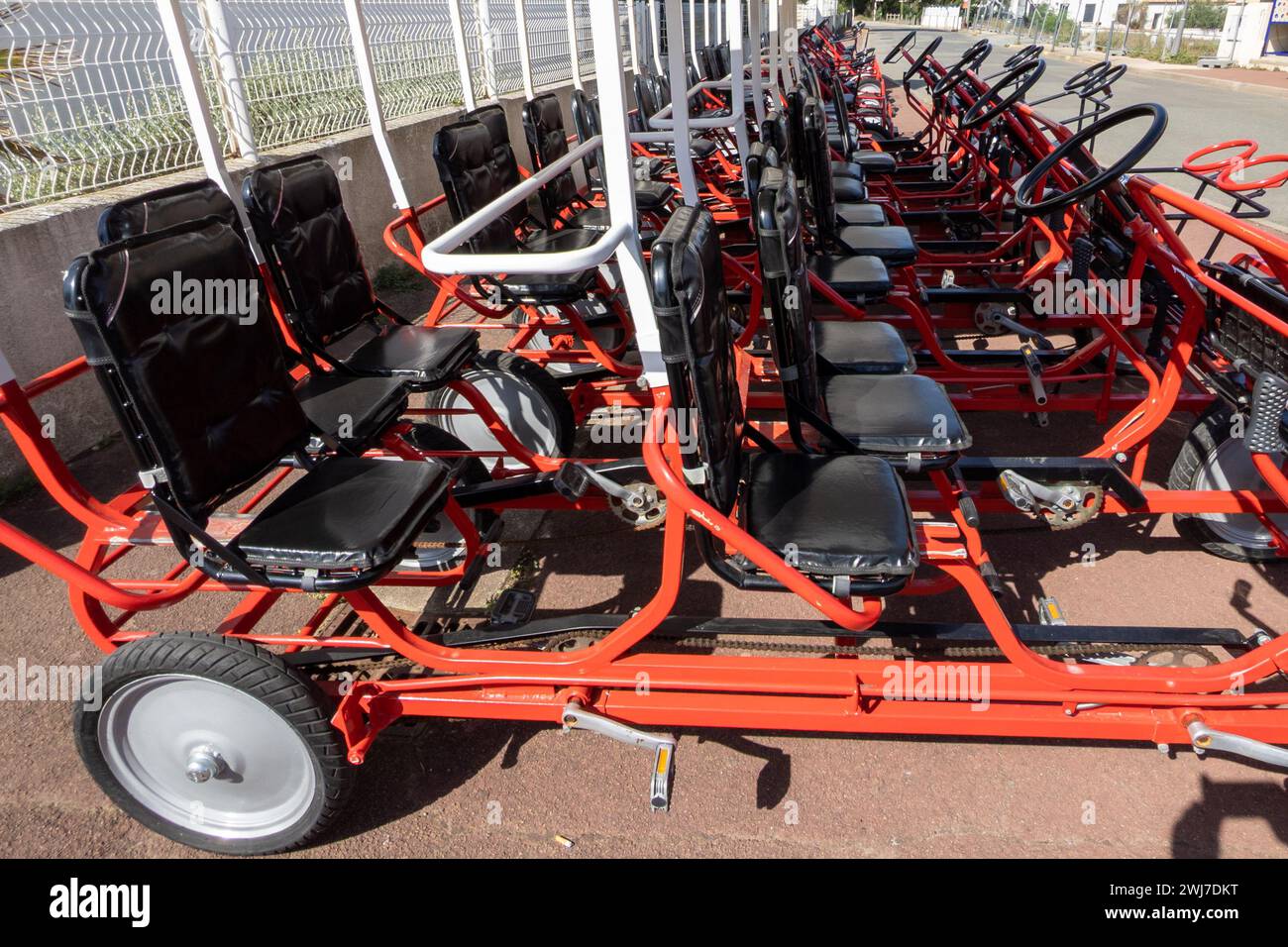 tourist multi-seater pedal car red lined up in front of the rental ...